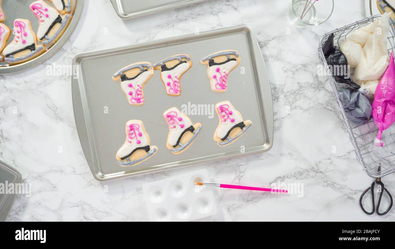 Flat lay. Brushing edible glitter on iced figure skate sugar cookies ...
