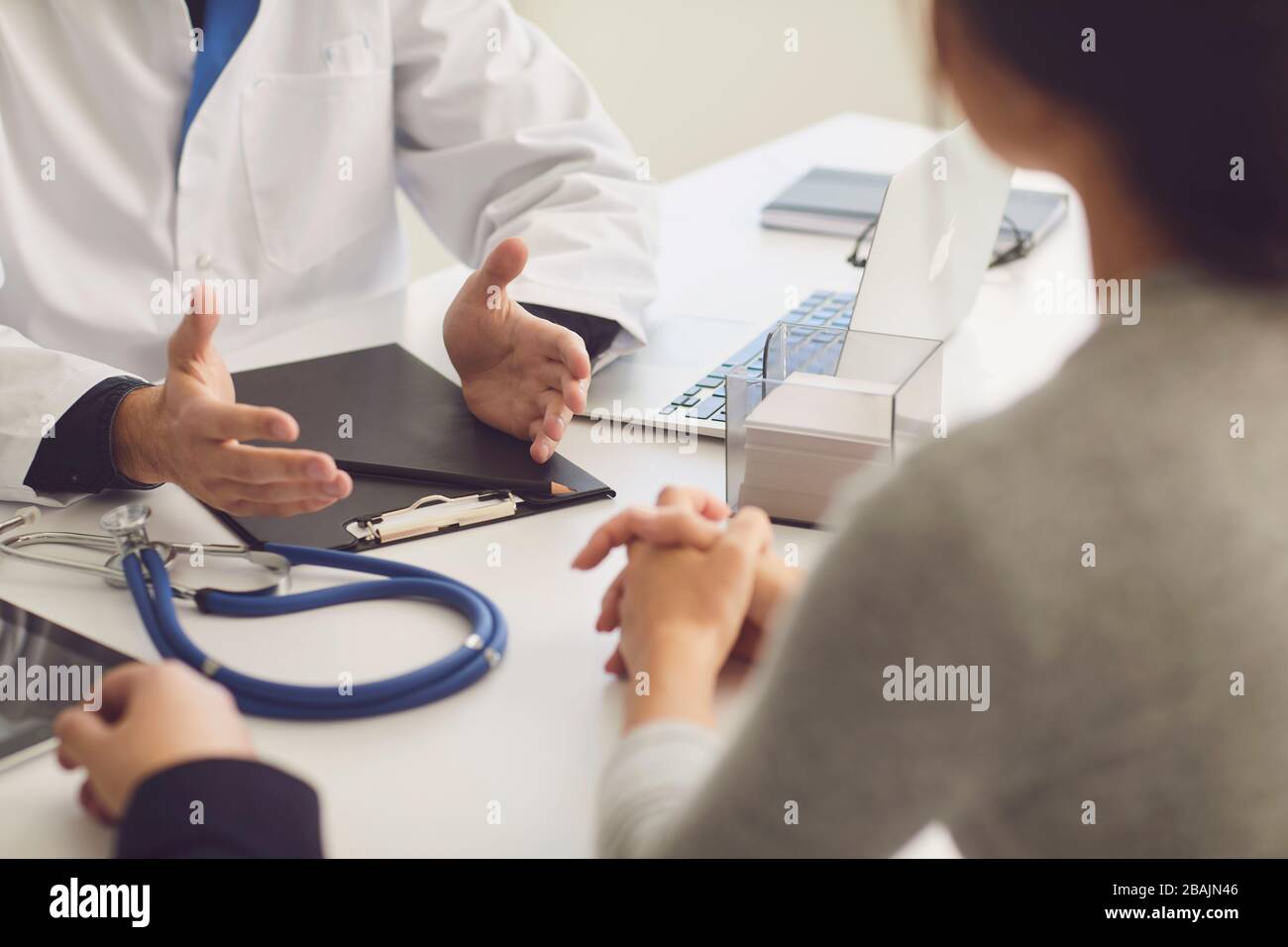 Confident doctor and couple patient sitting at the table in clinic ...
