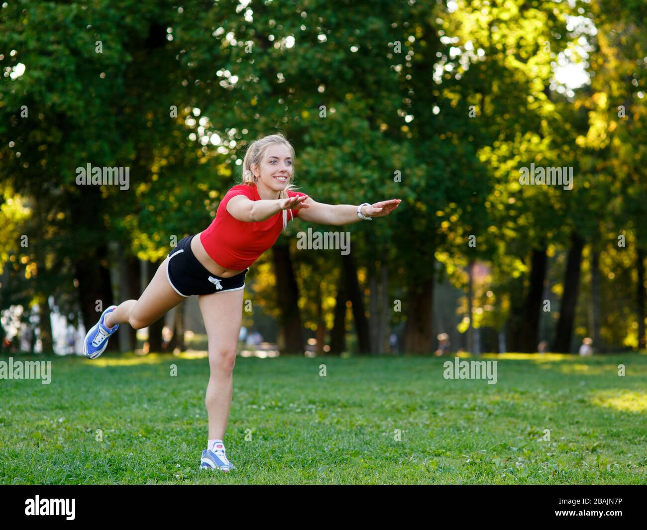 Young caucasian woman doing one leg balance pose, yoga warrior, outdoor ...