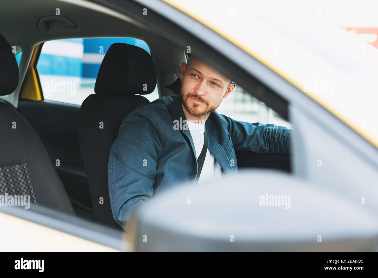 Friendly smiling bearded man taxi driver wearing blue suit inside ...