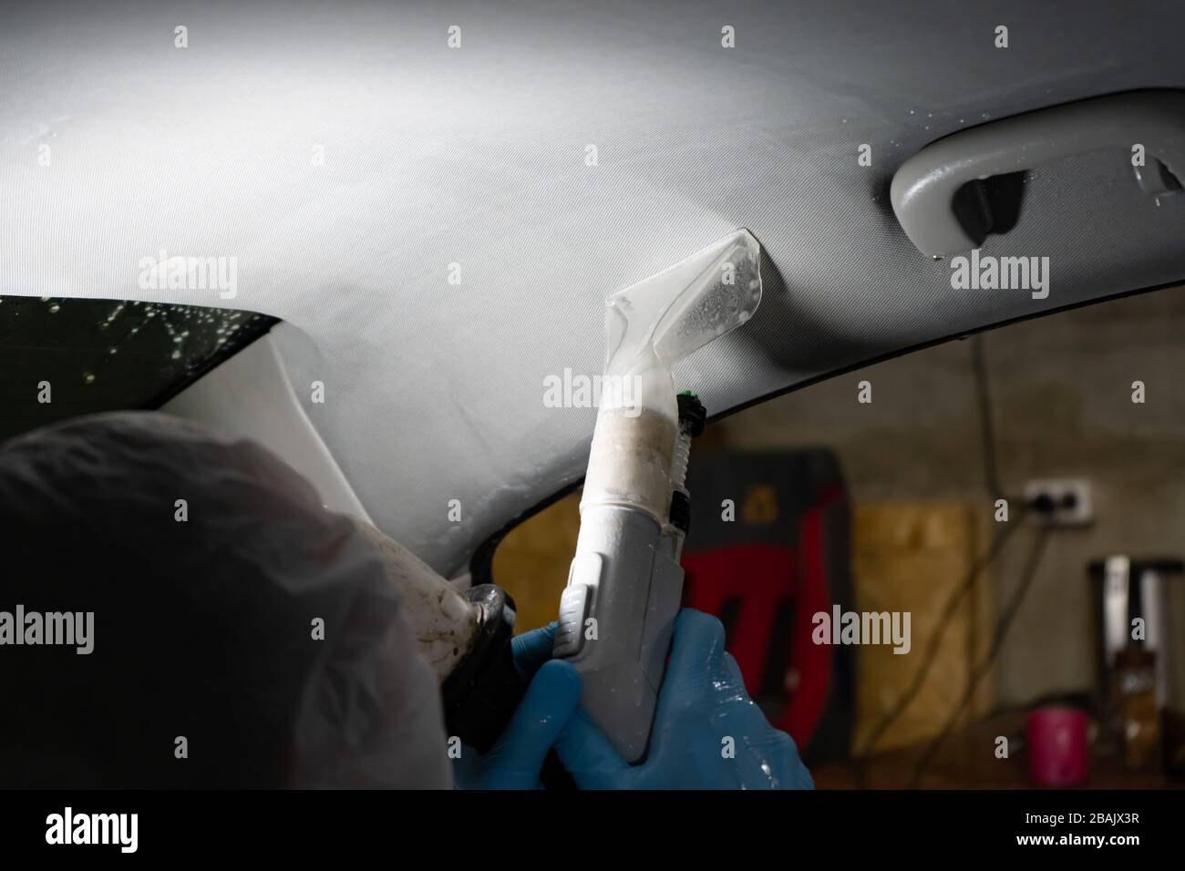 Dry cleaning of the car. Worker disinfects with a vacuum cleaner in a ...