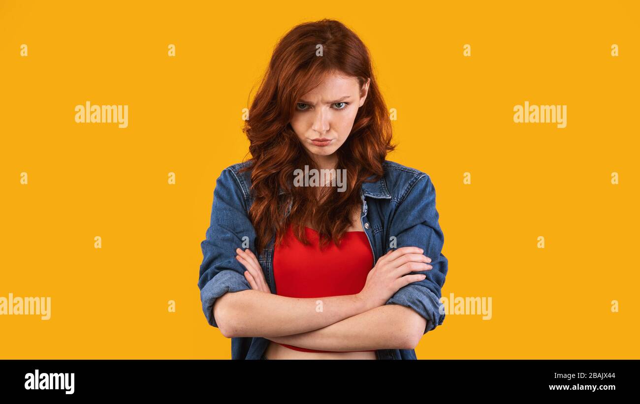 Sulky Teen Girl Crossing Hands Looking At Camera Posing Over Yellow ...