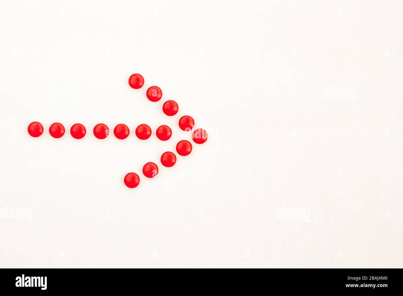 Red arrow made of pills or candies on white background Stock Photo - Alamy