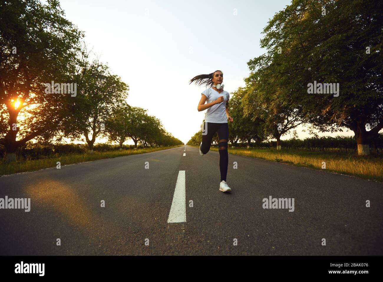 Girl runner runs on the road the sun at dawn Stock Photo - Alamy