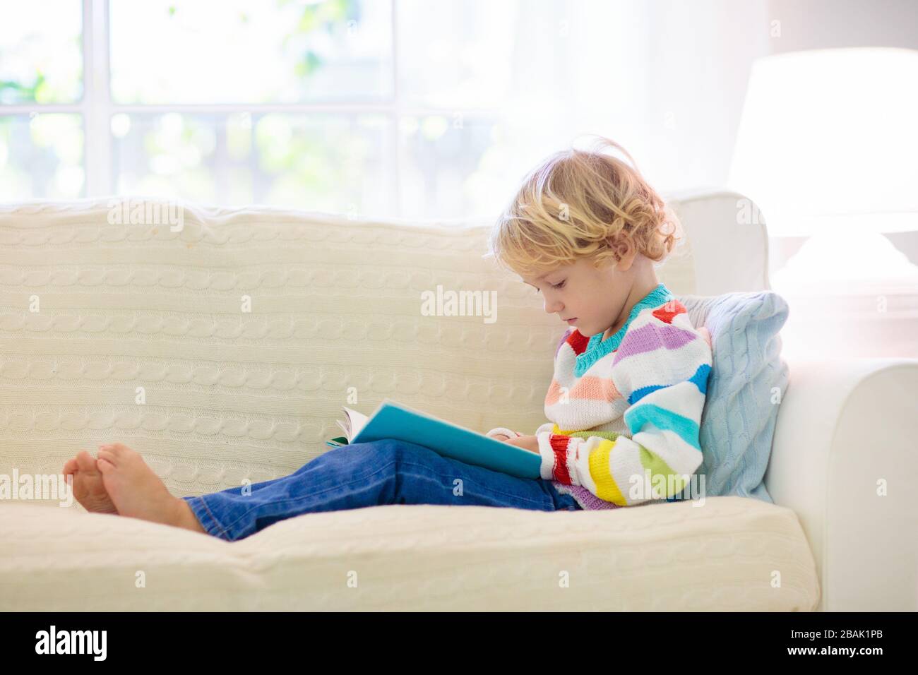 Child reading book. Kids read books. Little boy sitting on white couch ...