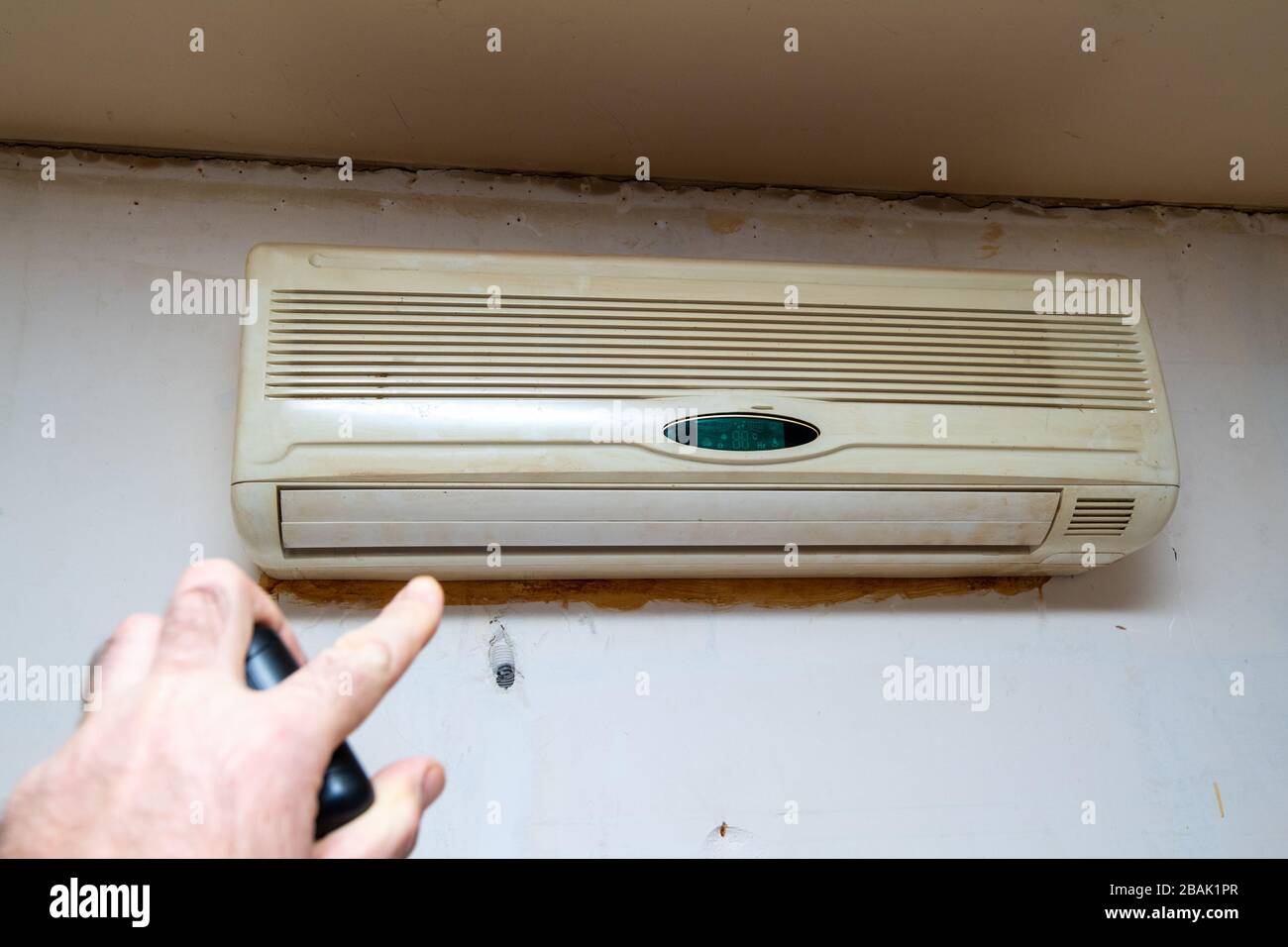 Male hand pointing to old rusty AC device on the wall of an old ...