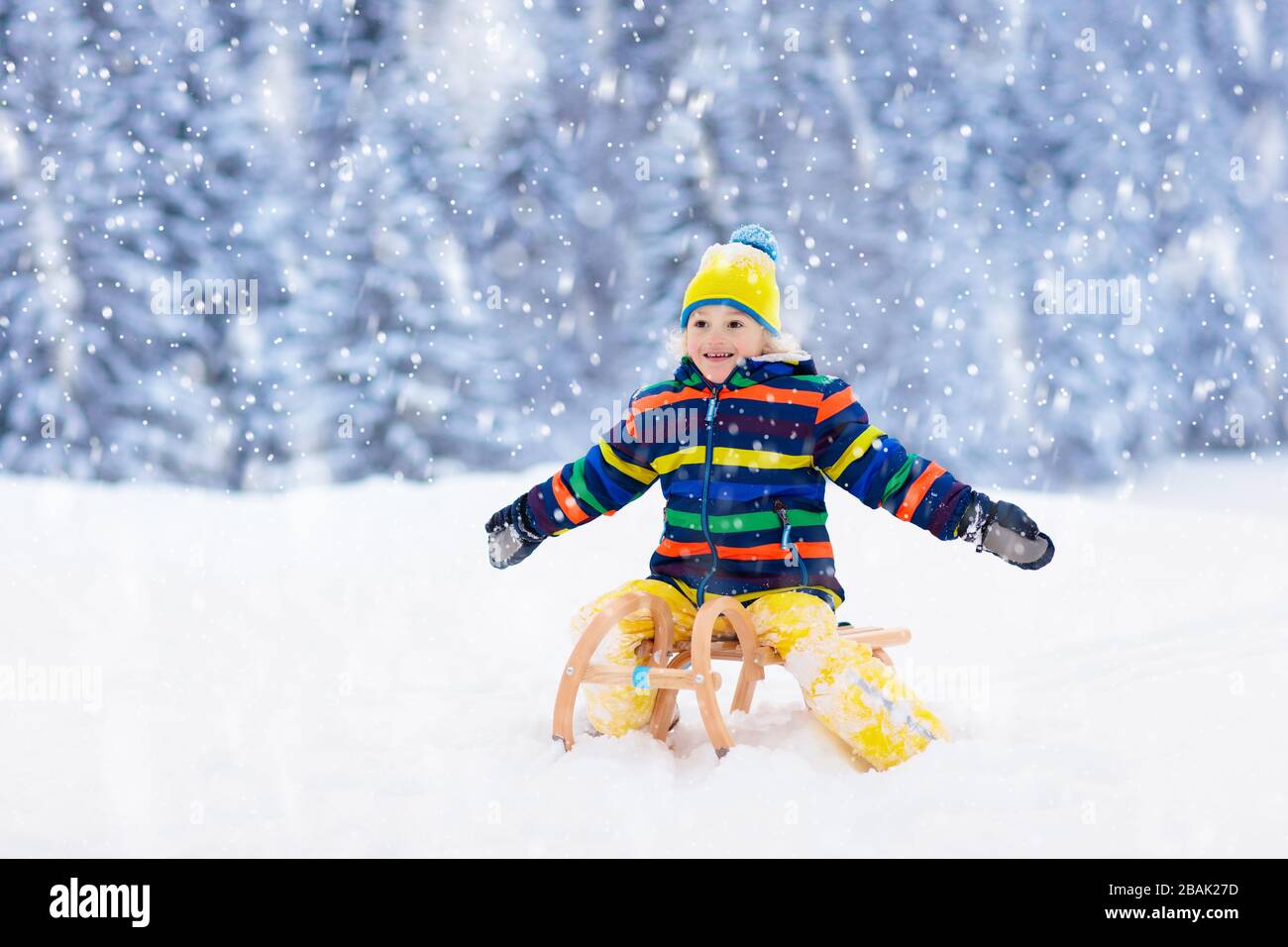 Little boy enjoying a sleigh ride. Child sledding. Toddler kid riding a ...