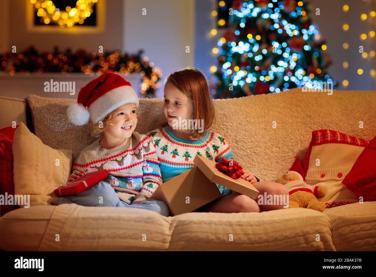 Children at Christmas tree and fireplace on Xmas eve. Family with kids ...