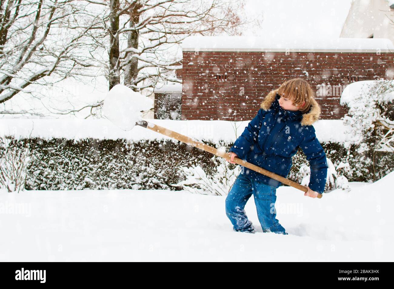 Child shoveling snow. Little boy with spade clearing driveway after ...