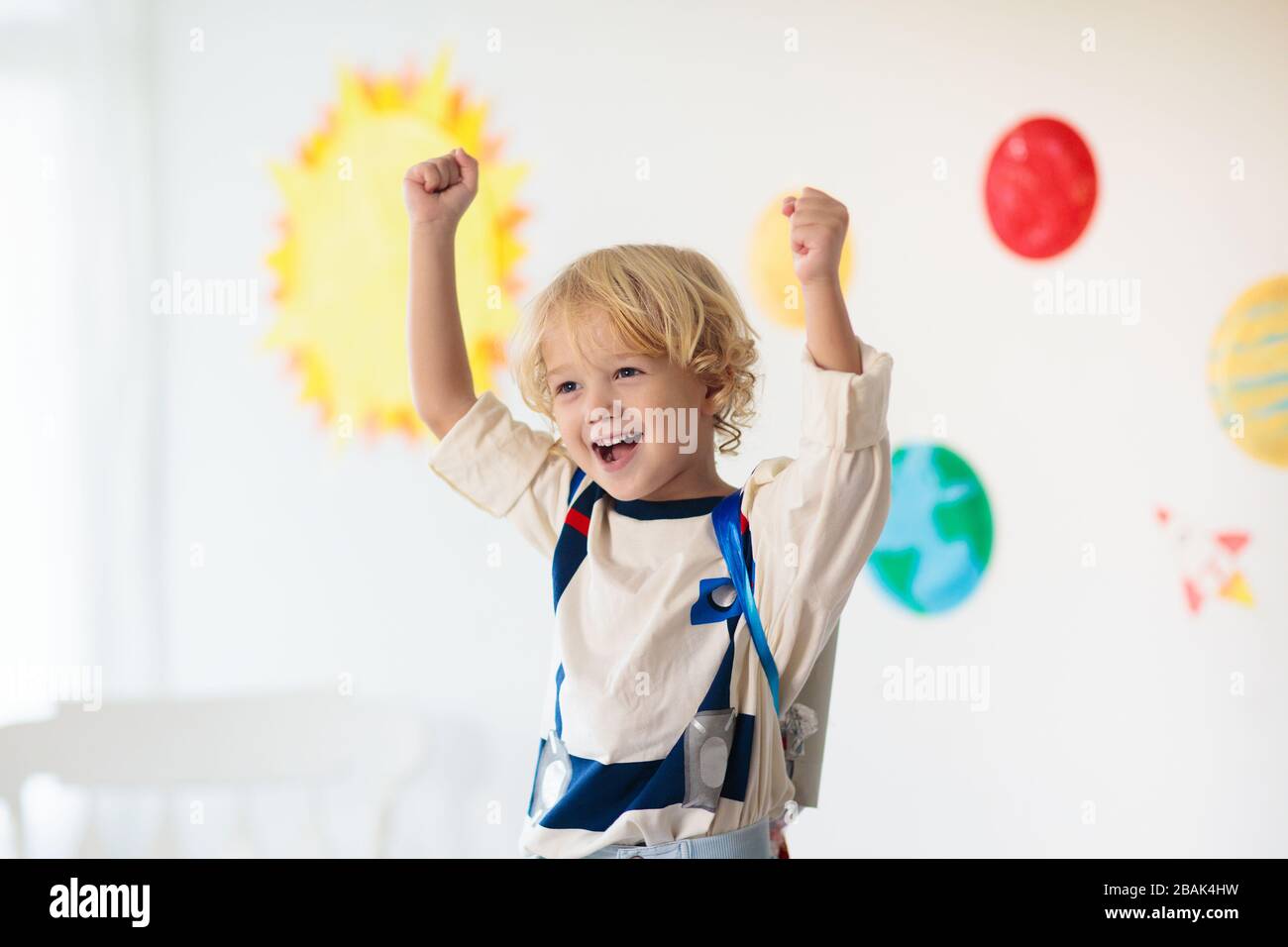 Kids play astronaut. Little boy in space costume jumping on bed with ...
