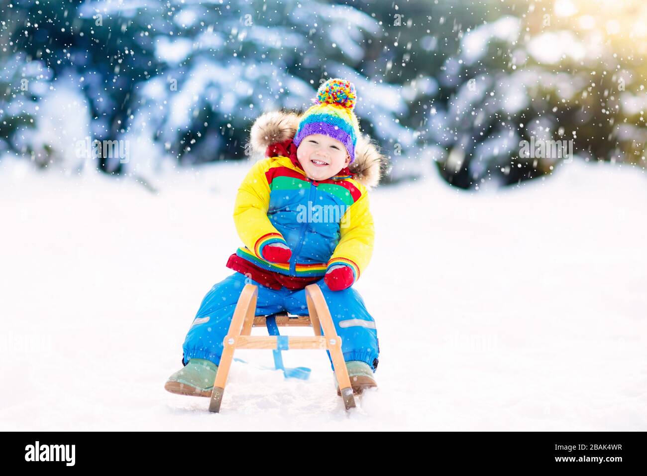 Little boy enjoying a sleigh ride. Child sledding. Toddler kid riding a ...