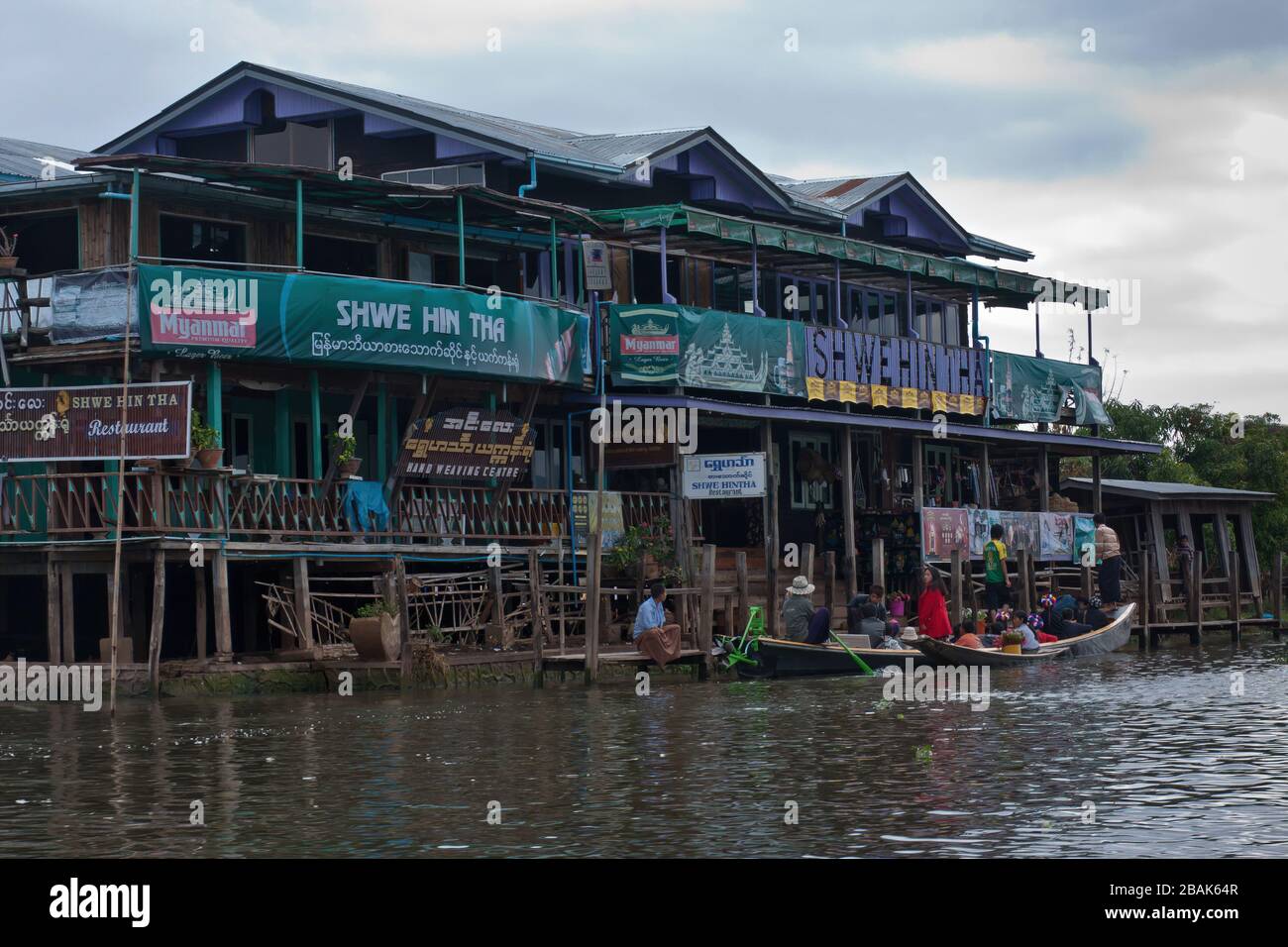 A restaurant in the stilt house and moored boats with people, Inle Lake ...