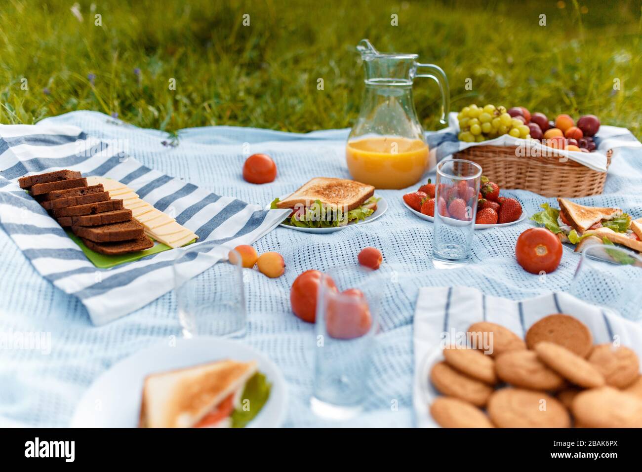 summer picnic on the grass with an open picnic basket, fruit, with ...