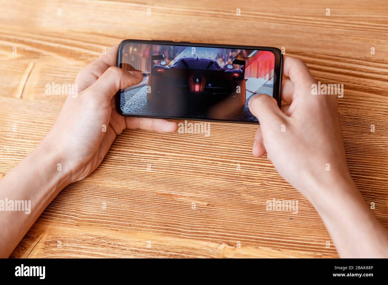 a young guy plays asphalt 9 mobile game on the phone. Smartphone ...