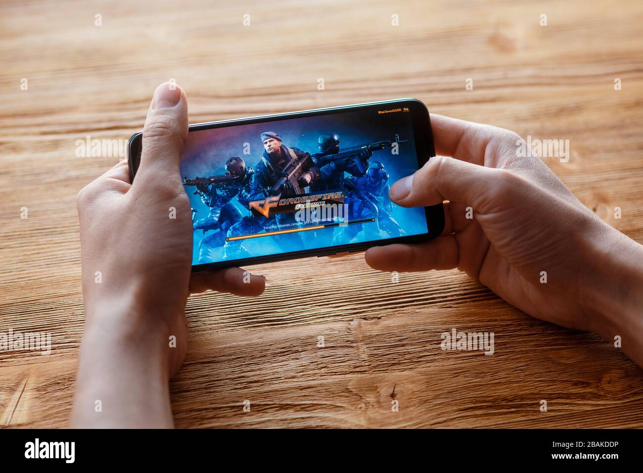 a young guy plays crossfire legend mobile game on the phone. Smartphone ...