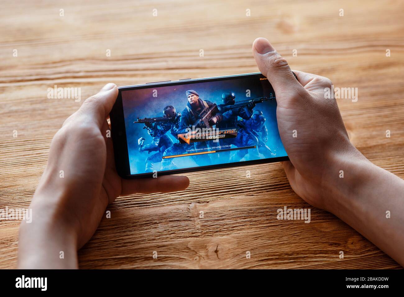 a young guy plays crossfire legend mobile game on the phone. Smartphone ...