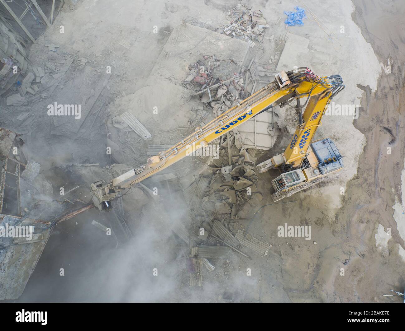 A high reach demolition excavator pulling down a building at a cement ...