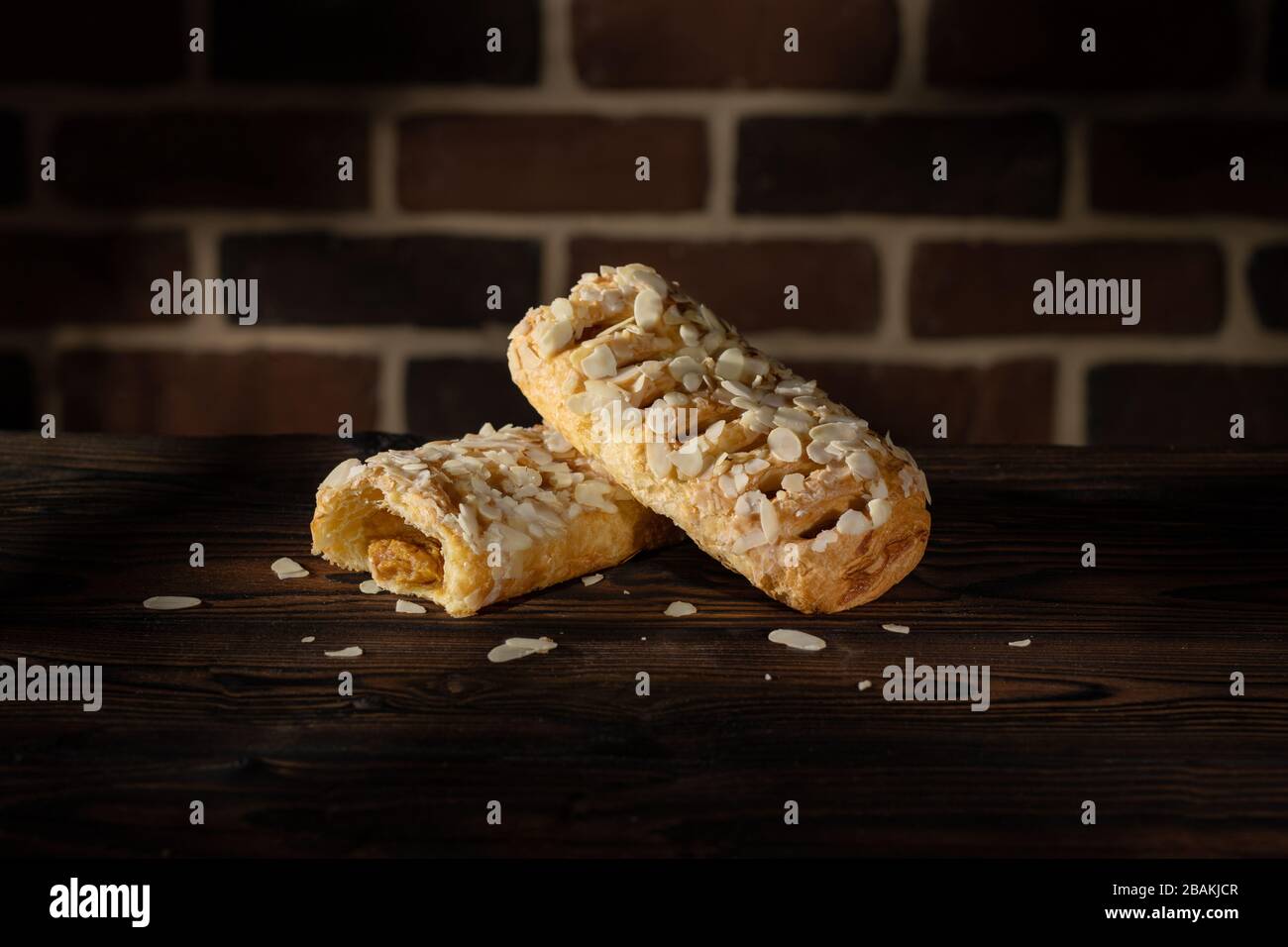 Caramel strudel with almond flakes on wood table and brick wall ...