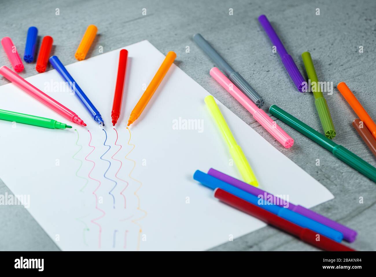 many multi-colored markers for drawing with drawings on white paper ...