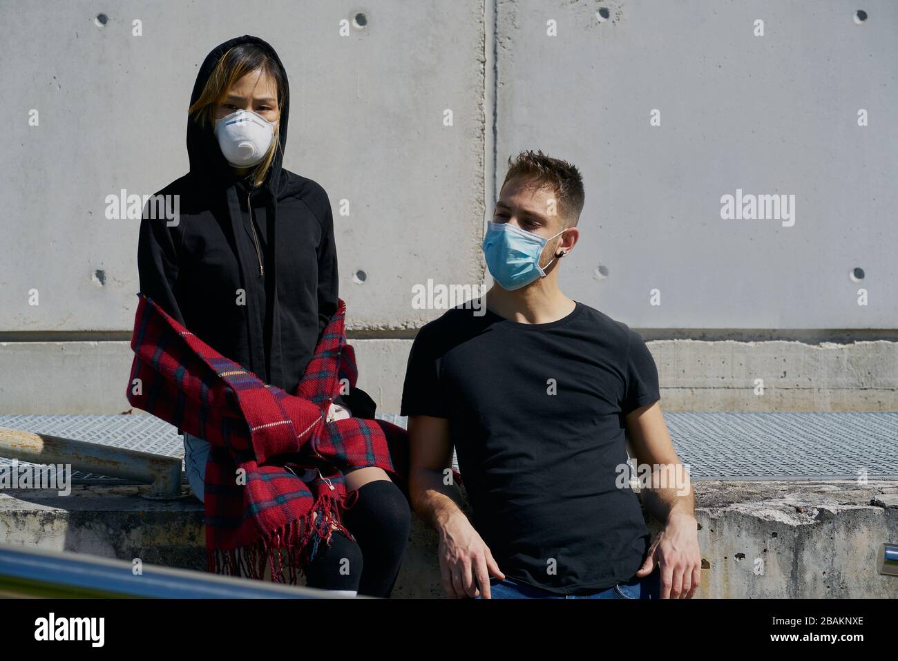 Caucasian male and Asian female wearing medical masks as a defense ...