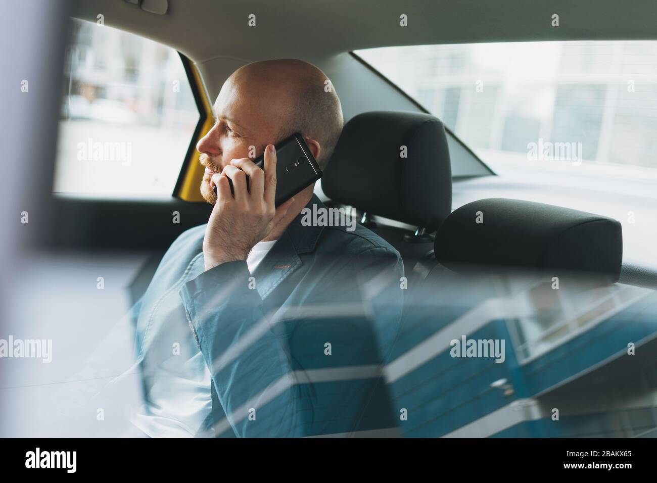 Handsome bald bearded man businessman in suit using mobile phone inside ...