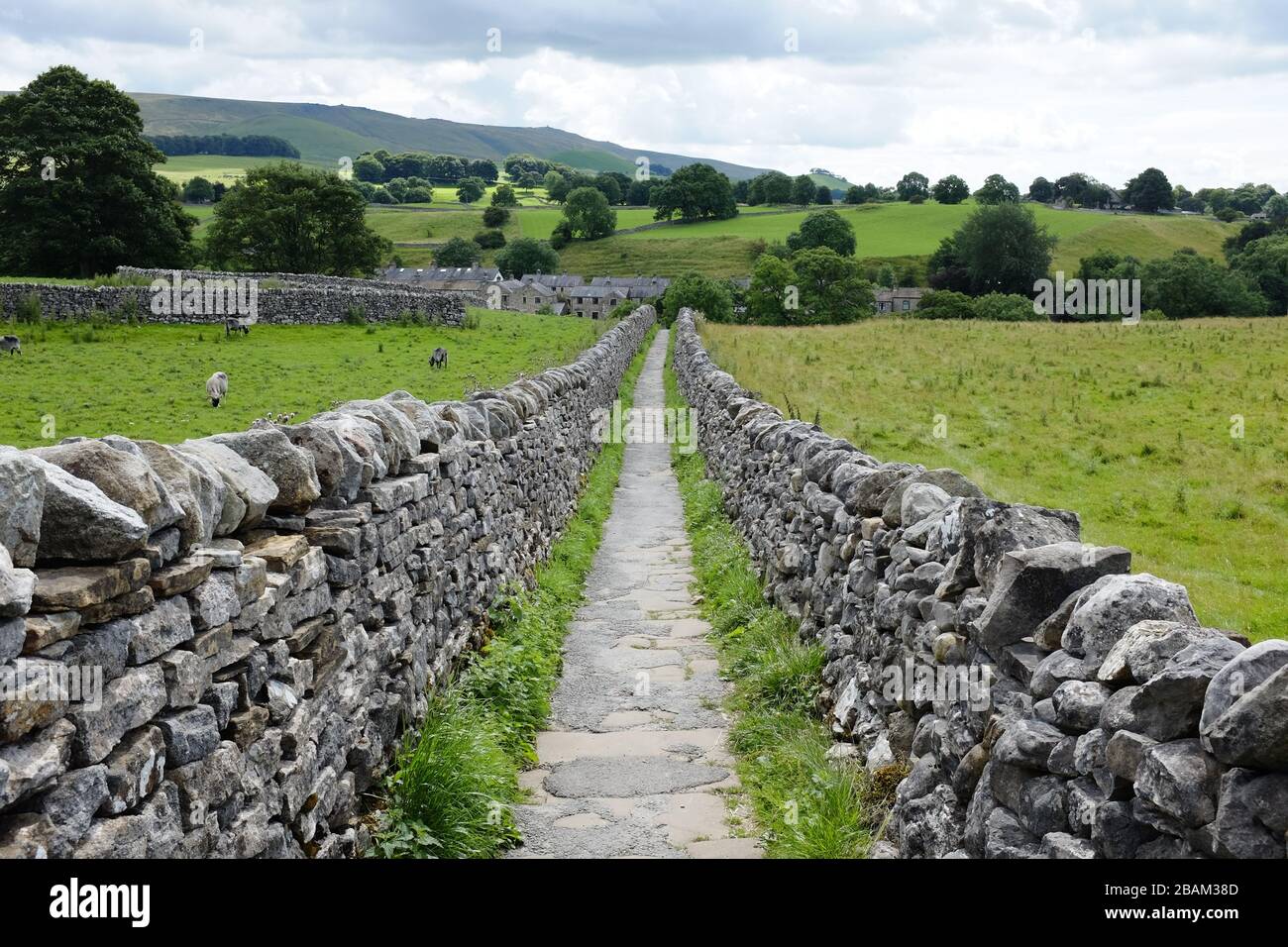 A walker's footpath with rock walls on each side, through the hills of ...