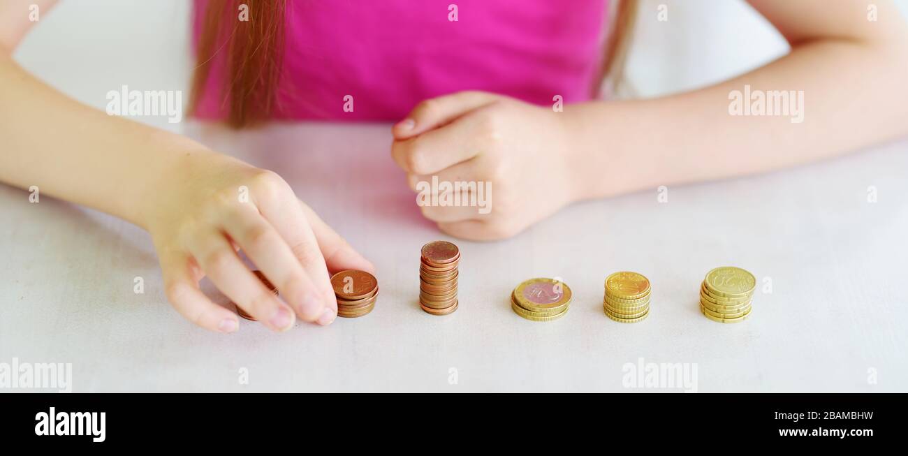 Closeup of kid's hands and piles of coins. Child learning how to count ...