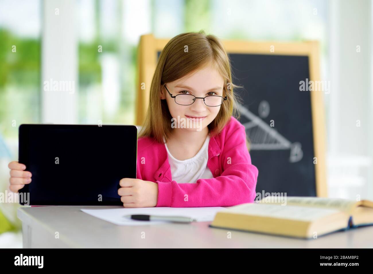 Smart schoolgirl doing her homework with digital tablet at home. Child ...