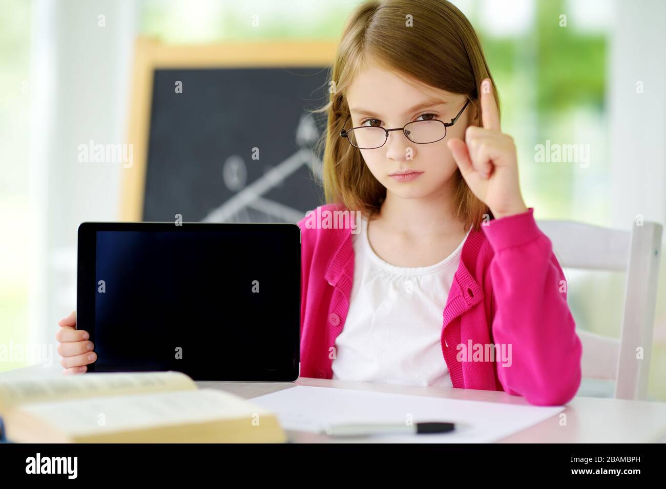 Smart schoolgirl doing her homework with digital tablet at home. Child ...
