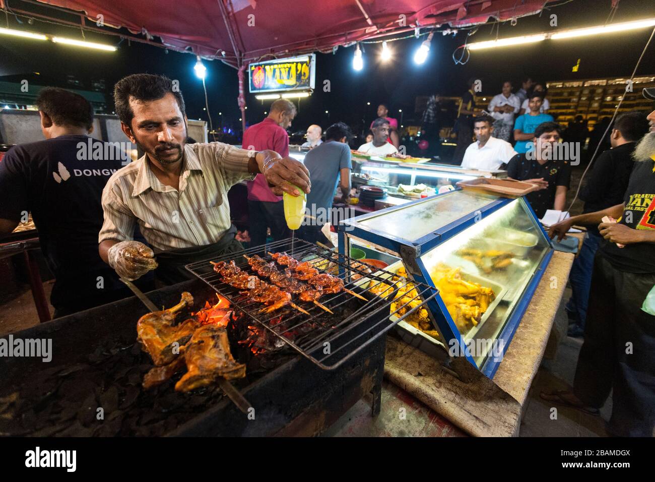 Local man grilling skewers at a street food stall at Galle Face Green ...