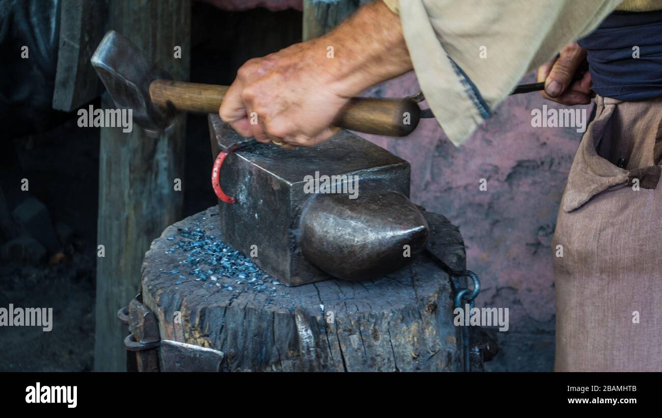 Blacksmith's hands hammering out a tool Stock Photo - Alamy