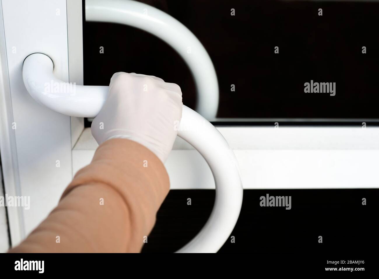 Woman opens the door in a public place wearing white latex protective ...