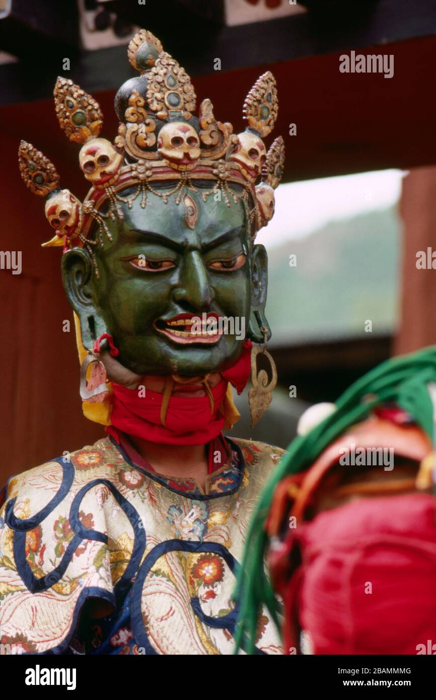 A monk dancer wearing a larger mask prepares to enter the dance floor ...