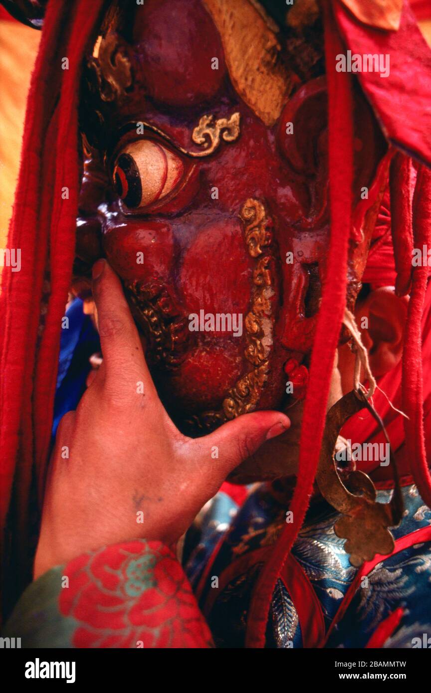A monk dancer adjusts his mask, displaying a small swastika tattoo on ...
