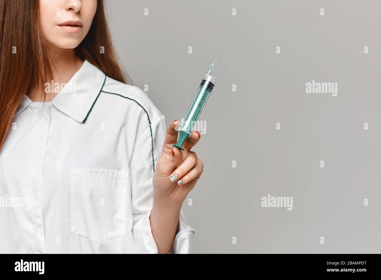 Medical syringe in the hand of a female doctor at the grey background ...