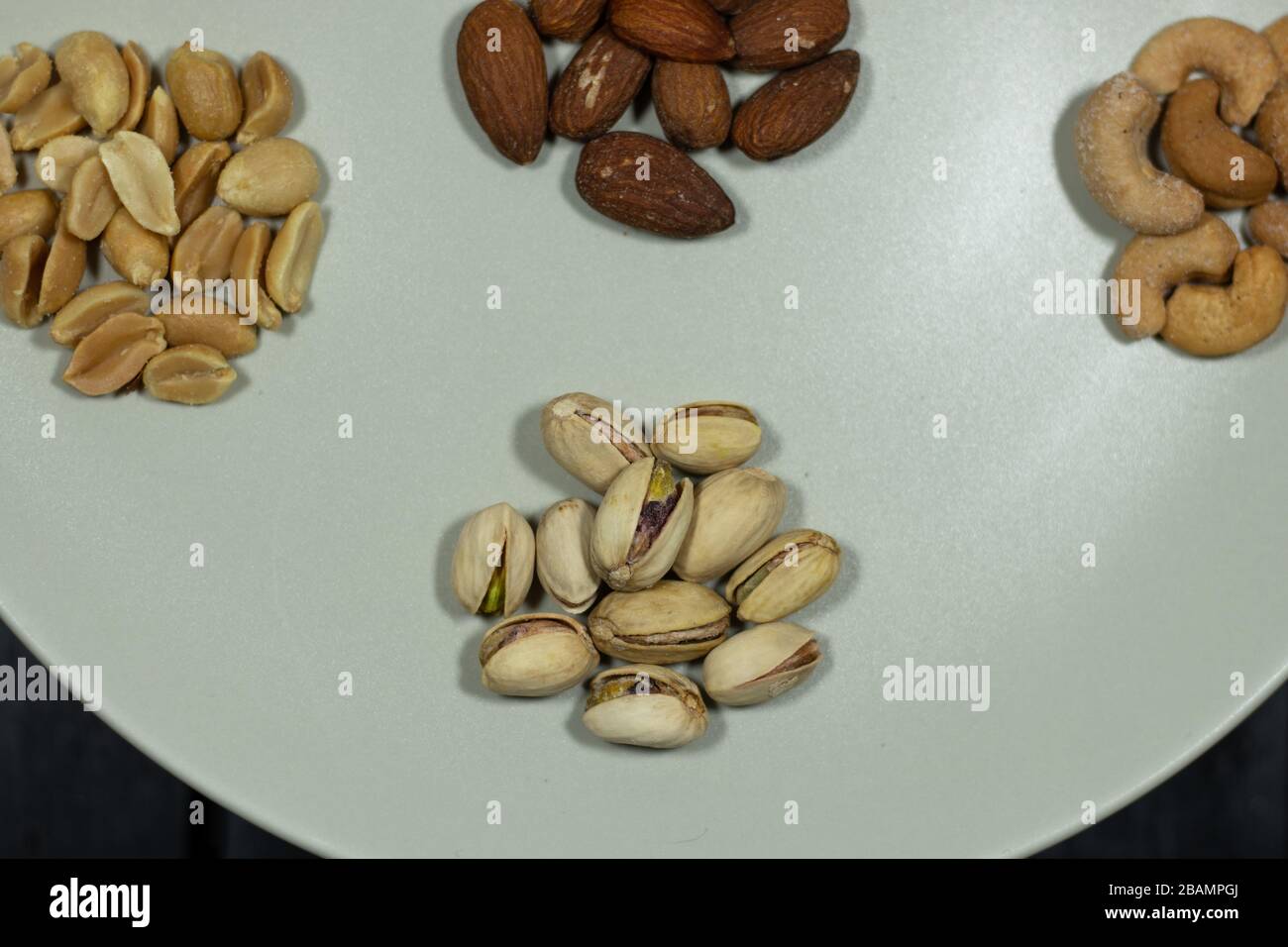 Different kinds of nuts in white dish top view Almonds, Pistachios ...