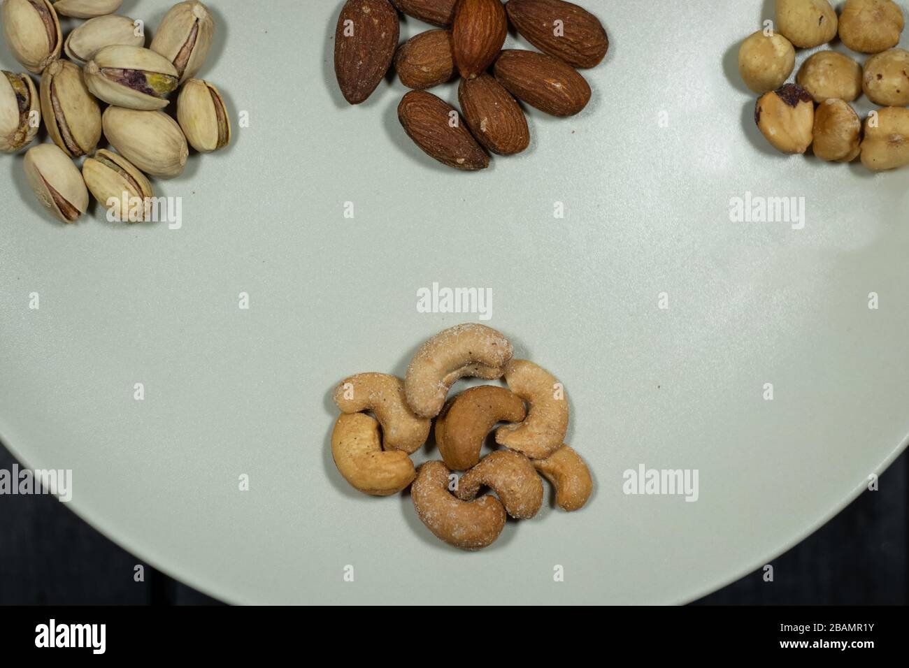 Different kinds of nuts in white dish top view Almonds, Pistachios ...
