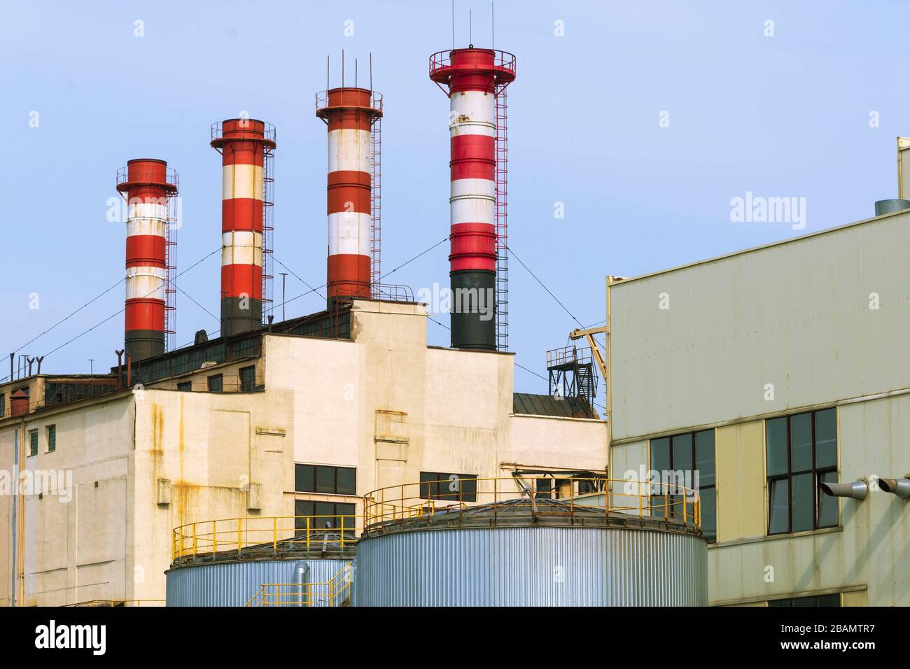 high factory exhaust pipes against a blue sky, urban air pollution ...