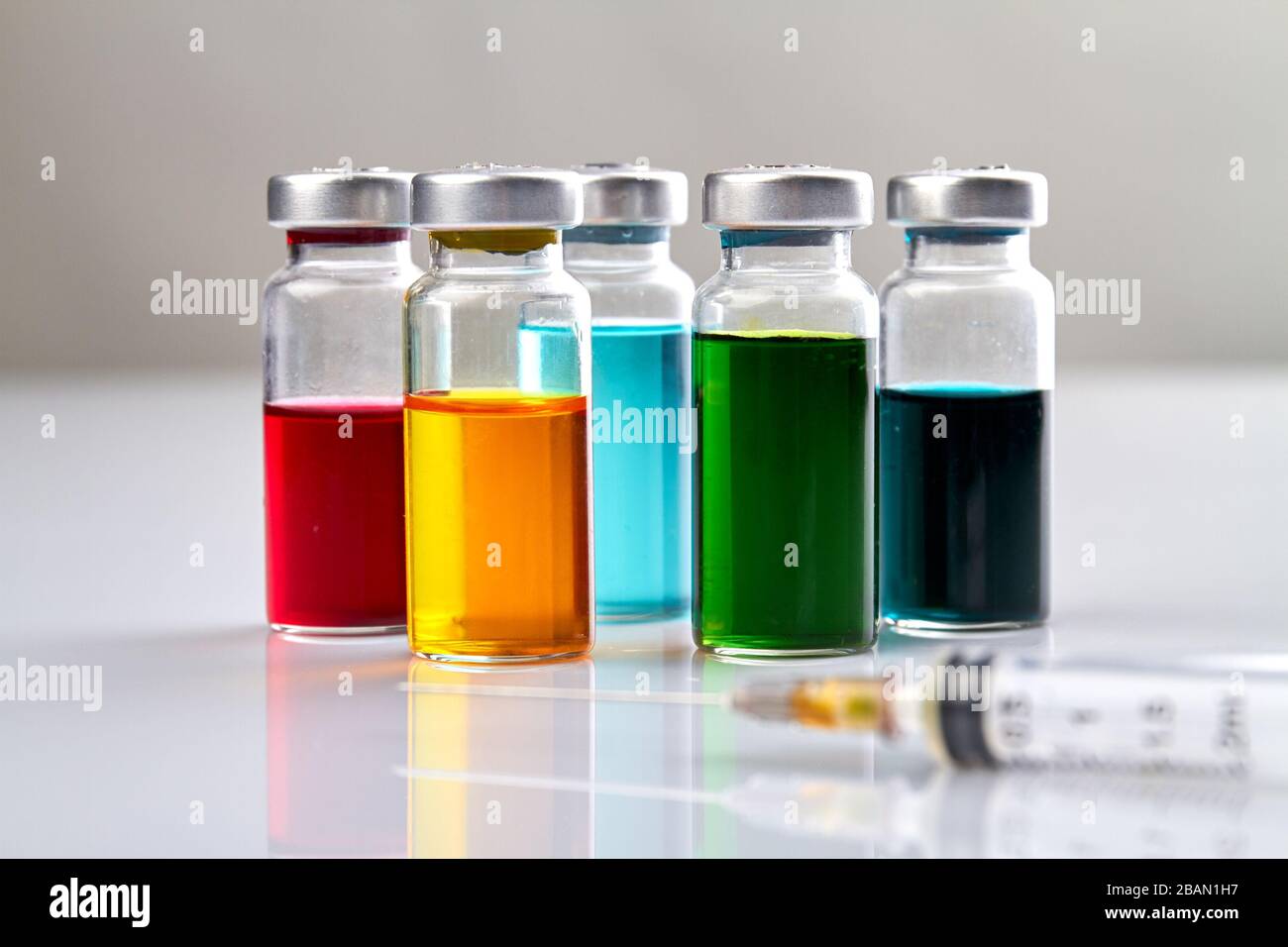 Glass vials with colored medicine liquid and syringe Stock Photo - Alamy