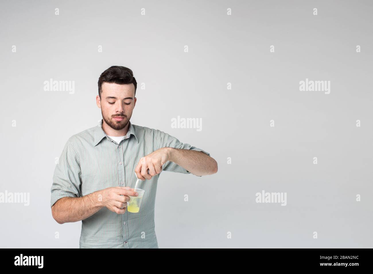 Young man isolated over background. Serious concentrated guy pouring ...
