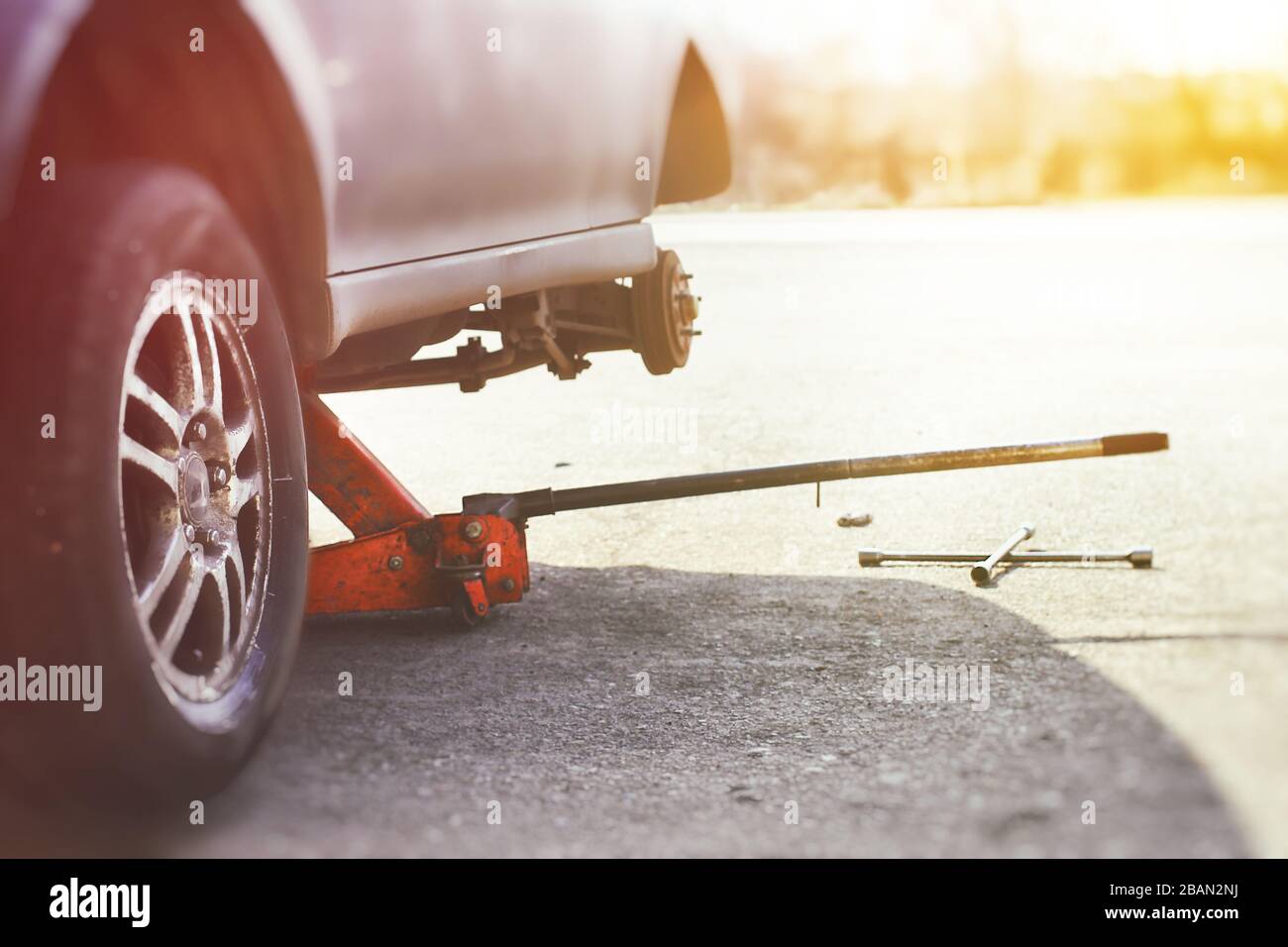 A red hydraulic floor jack and wheel wrench ready for wheel repair ...