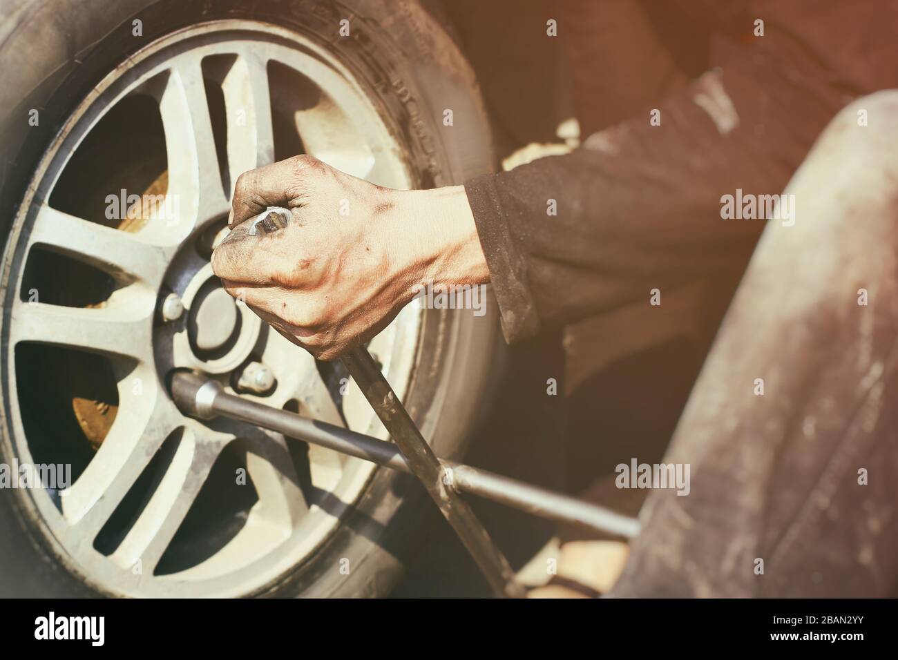 A man tightens the nuts with wheel wrench on the car wheel Stock Photo ...