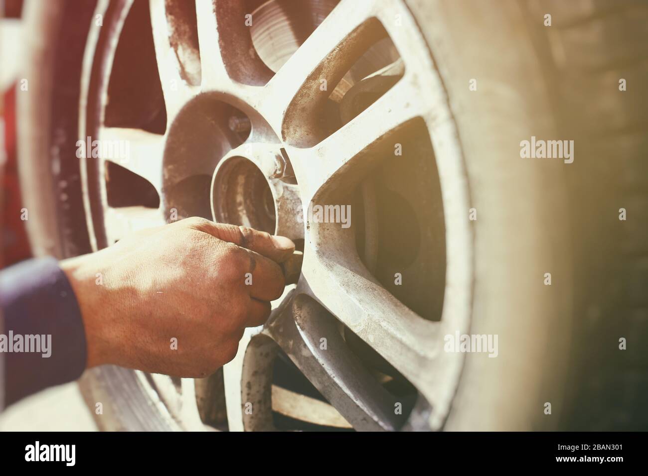 A man tightens the nuts on the car wheel Stock Photo - Alamy
