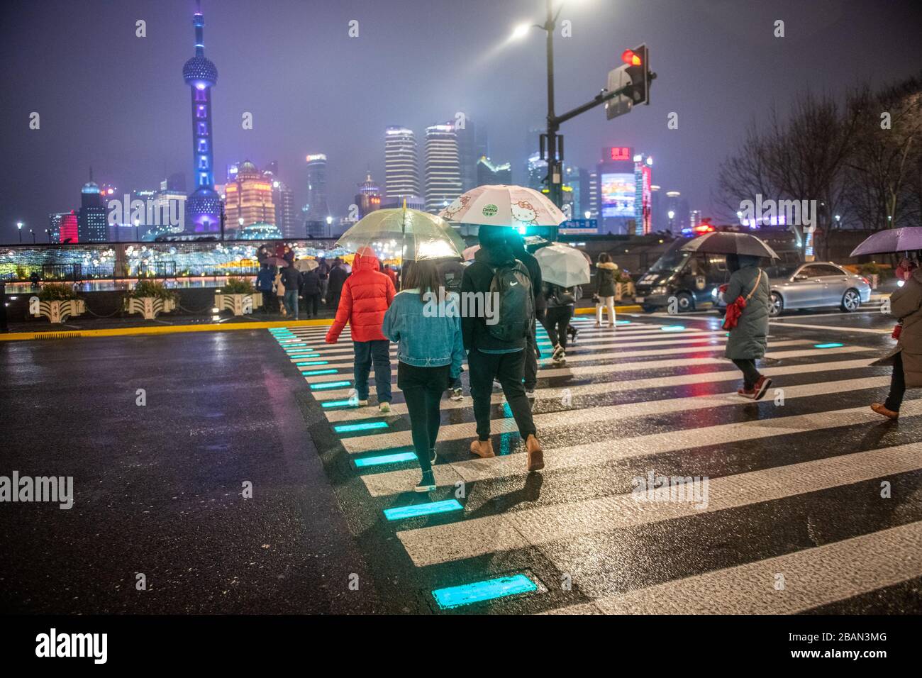 A busy crosswalk backed by the bright cityscape of Shanghai, China ...