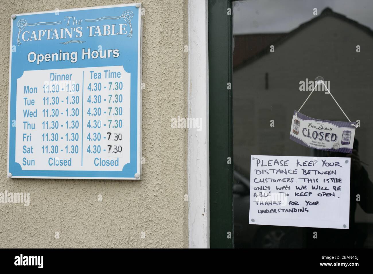 Social distancing warning sign on closed fish and chip shop door ...