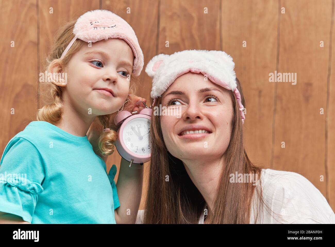 Mom with a small daughter in sleep masks yawn and hug each other. Keep ...