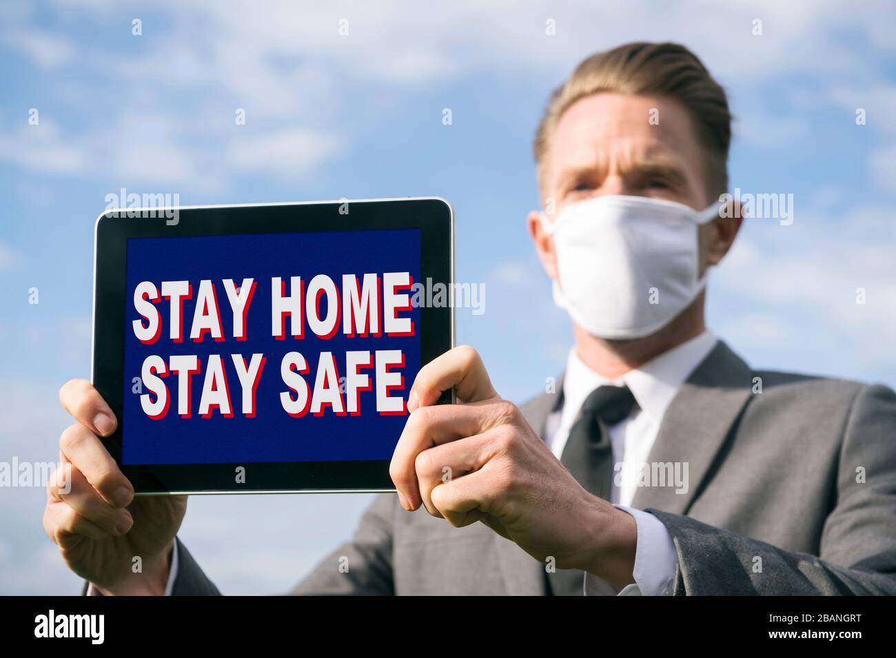 Businessman wearing COVID-19 protective face mask holding a tablet with ...