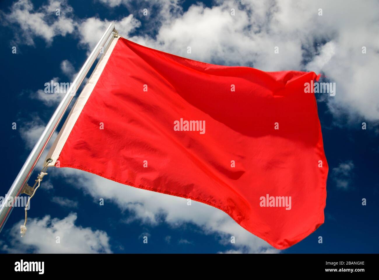 Bright red warning flag waving outdoors under sunny blue sky Stock ...