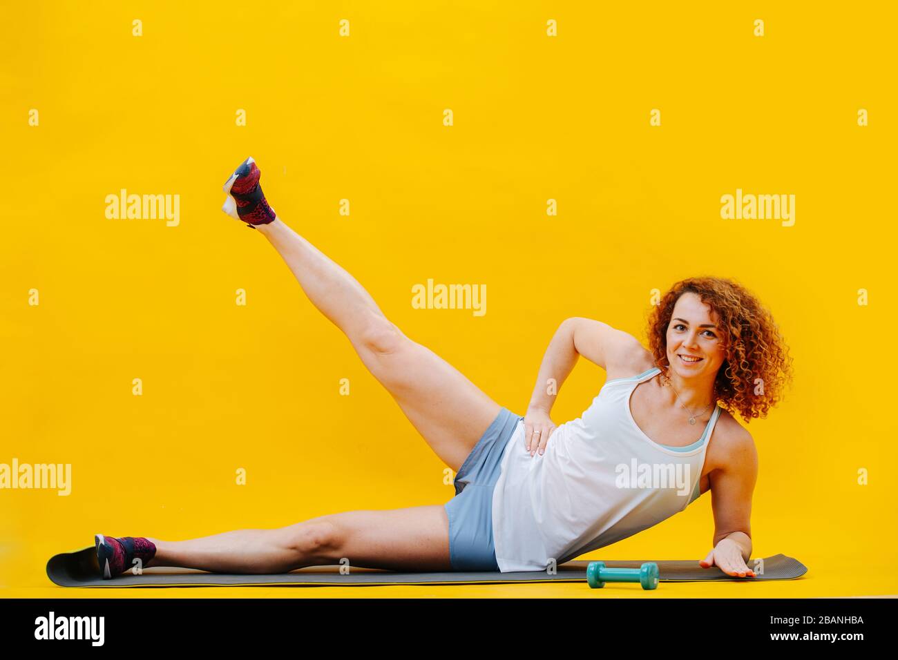 Girl lying on the mat does a warm-up, raising her leg Stock Photo - Alamy