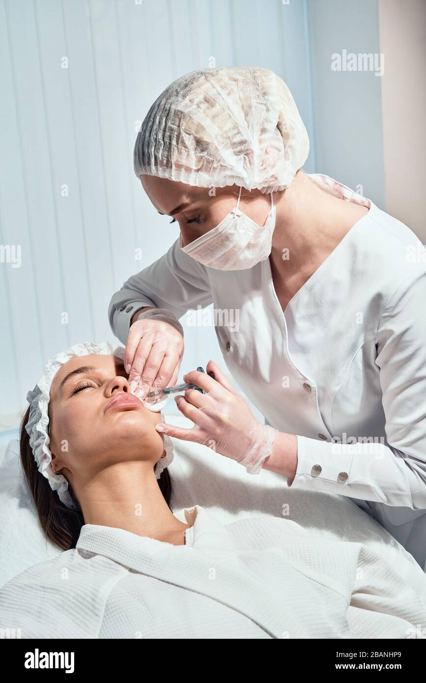 lip shape correction procedure in a cosmetology salon. The specialist ...